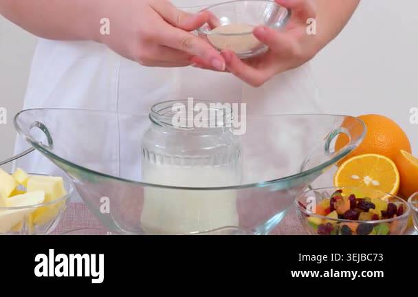 female pastry chef pours dry yeast into glass jar and carefully mixes ...