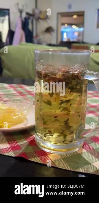 glass of herbal tea with lavender, rose petals, green tea leaves sits ...