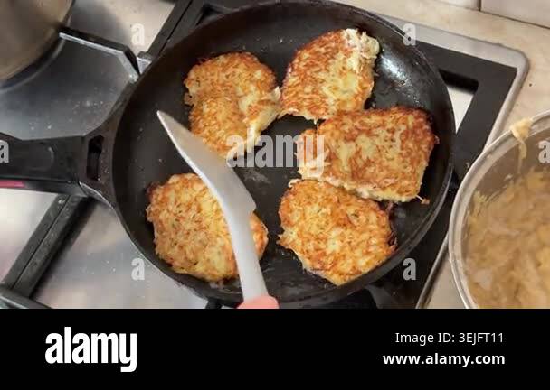 Golden potato pancakes sizzling in hot oil on frying pan while homemade ...