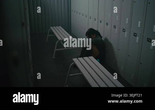 Woman Sitting Alone on Floor, Leaning Against Lockers, Overwhelmed by ...