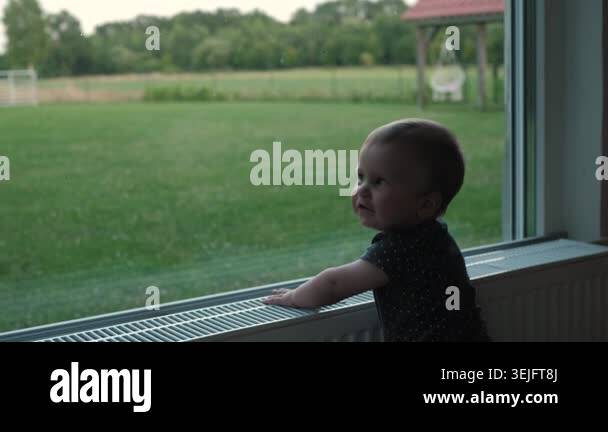 Child observes garden. Small child peers through window with curiosity ...