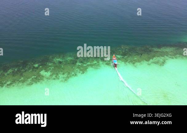 A longtail boat in a turqouse colored ocean with clear water at Koh ...