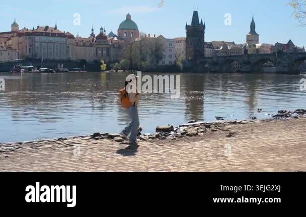 Discover the beauty of Prague as a traveler strolls along the Vltava ...