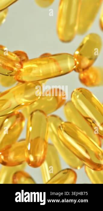 Golden softgel capsules shimmering in warm light, omega supplement ...