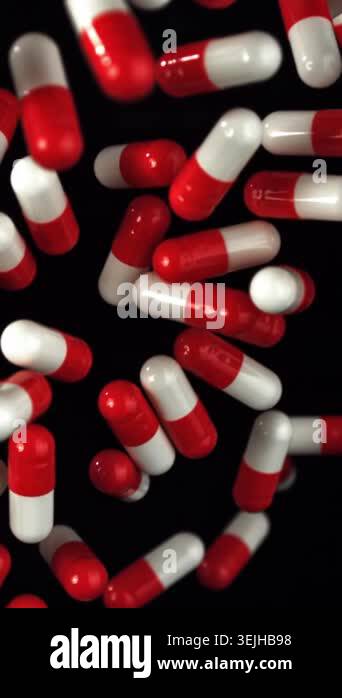 Red and white capsules swirling against black background, dynamic ...