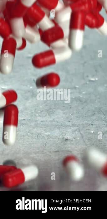 Red white capsules spilling on metal tabletop industrial closeup Filmed ...