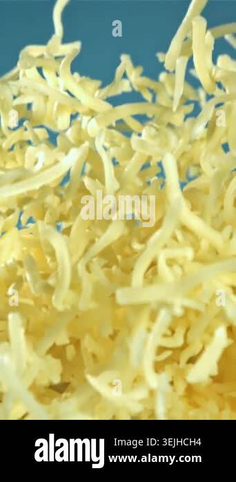 Shredded cheese flies up. On a blue background. Filmed on a high-speed ...