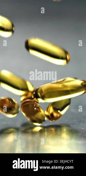 Golden gel pills drop and roll on dark reflective plane, premium mood ...