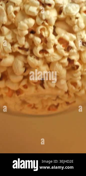 A bowl of popcorn falls on a yellow background. Filmed on a high-speed ...