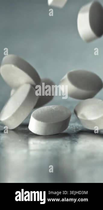 White round tablets falling and landing on metallic surface, Filmed on ...