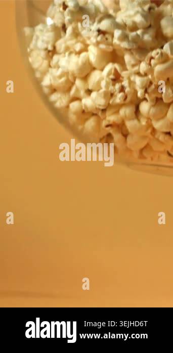 A bowl of popcorn falls on a yellow background. Filmed on a high-speed ...