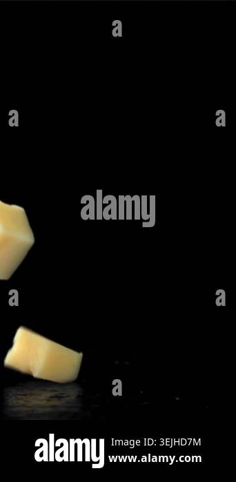 Super slow motion pieces of cheese on black background. Filmed on a ...