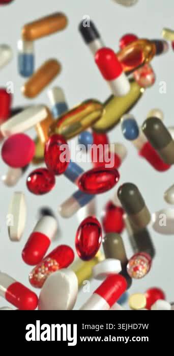 Colorful capsules falling against pale grey background, product Filmed ...