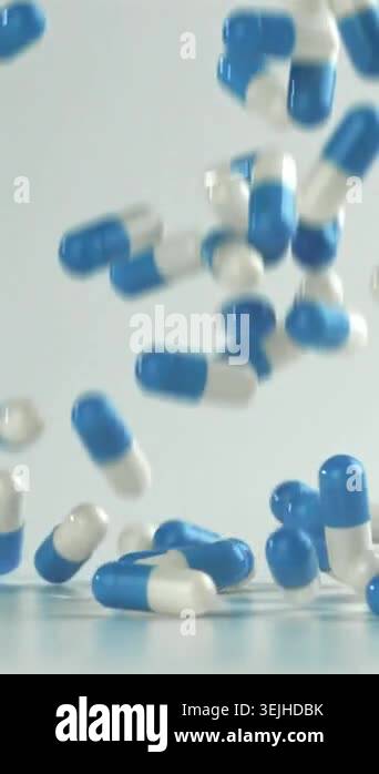 Blue white capsules bouncing on neutral surface clinical slow motion ...