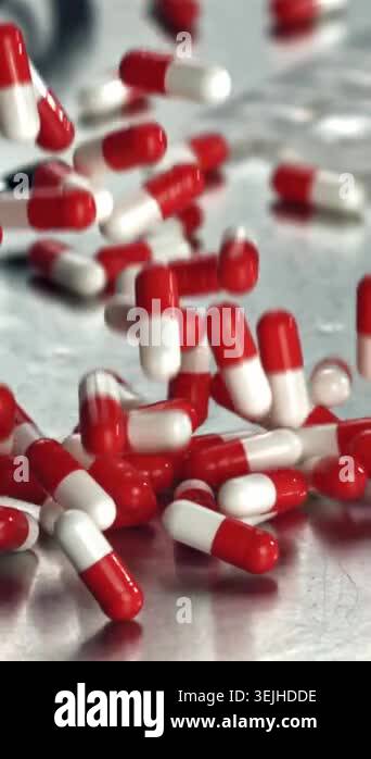 Red and white capsules spill near stethoscope on stainless surface ...