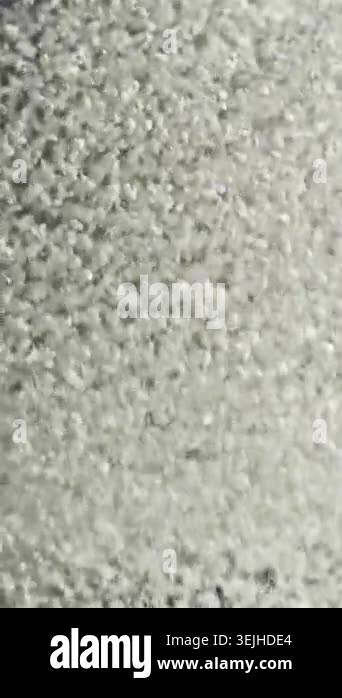 The flour is sifted through a sieve. On a black background. Filmed on a ...