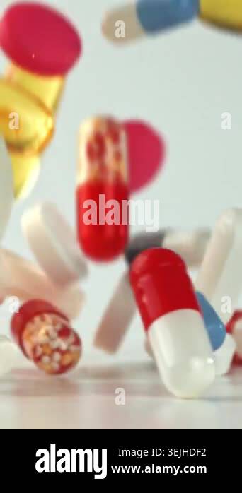 Assorted vitamins cascade onto white counter suggesting morning Filmed ...
