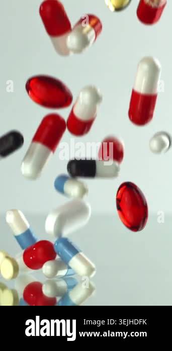 Mixed capsules and softgels cascading onto white surface, colorful ...