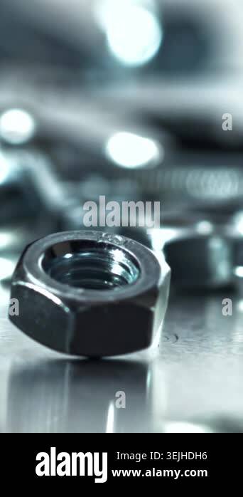 Assorted screws and nut scattered across surface. Shallow focus Filmed ...