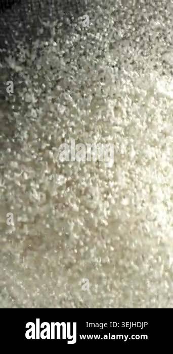 The flour is sifted through a sieve. On a black background. Filmed on a ...