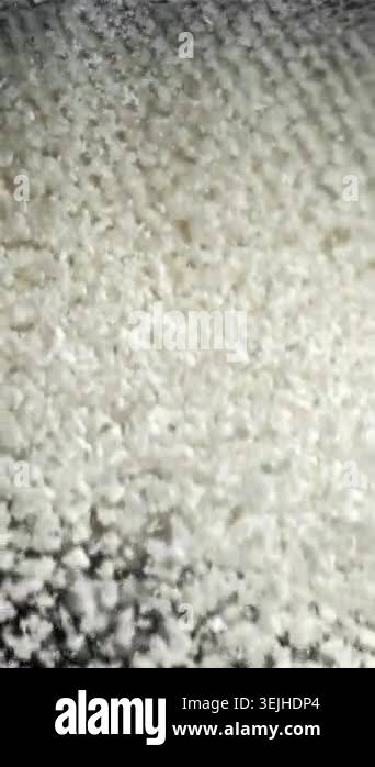 The flour is sifted through a sieve. On a black background. Filmed on a ...