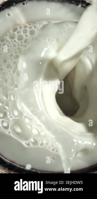 Milk is poured over half a coconut. Filmed on a high-speed camera at ...