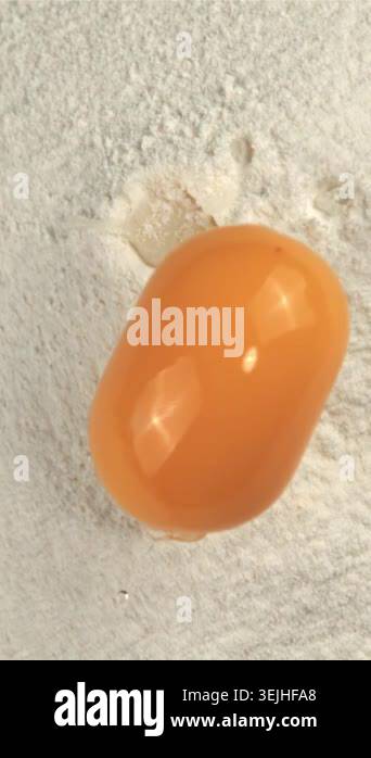 Super slow motion in a pile of flour falls a fresh egg. Top view. Macro ...