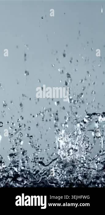 Splashes of water rise up and rotate in flight. On a blue background ...