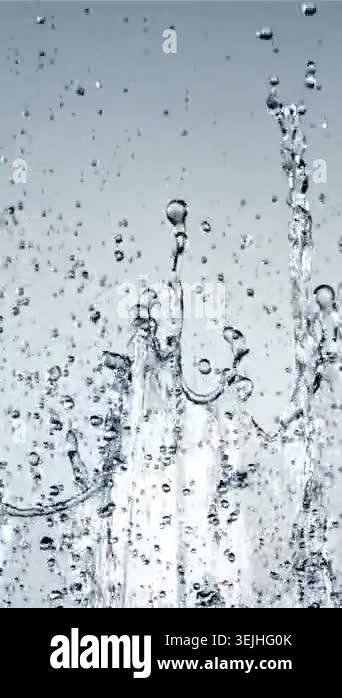 Splashes of water rise up and rotate in flight. On a blue background ...