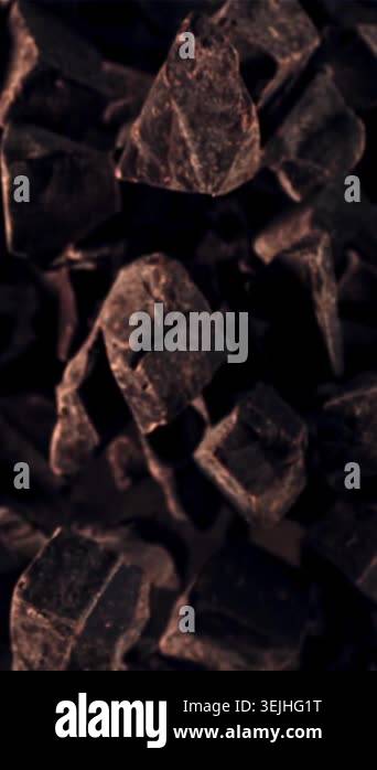 Pieces of chocolate rotate in flight. Against a dark background. Top ...