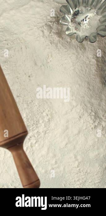 Super slow motion wooden rolling pin falls into a pile of flour on the ...