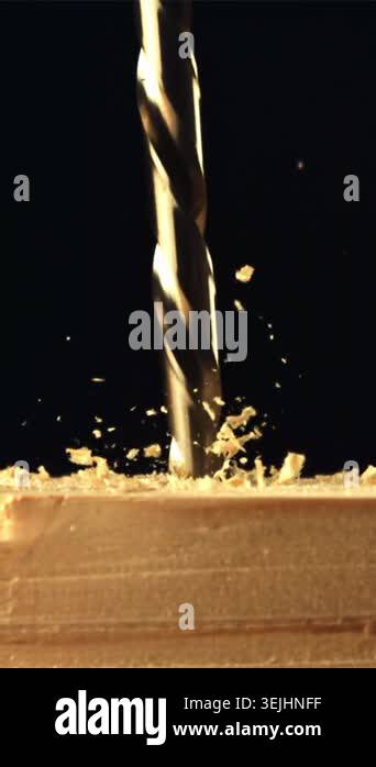 The drill drills wood with sawdust. On a black background. Filmed is ...