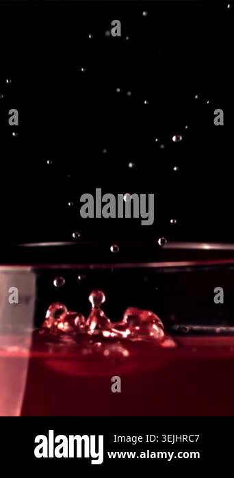 Super slow motion drop falls into a glass of wine with splashes.Filmed ...