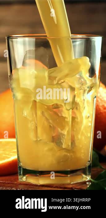 A stream of orange juice pours into the glass in a whirlpool. On a ...