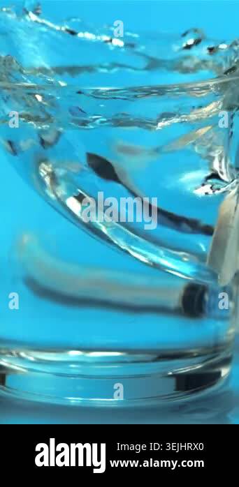 A tablet with splashes falls into a glass of water. On a blue ...
