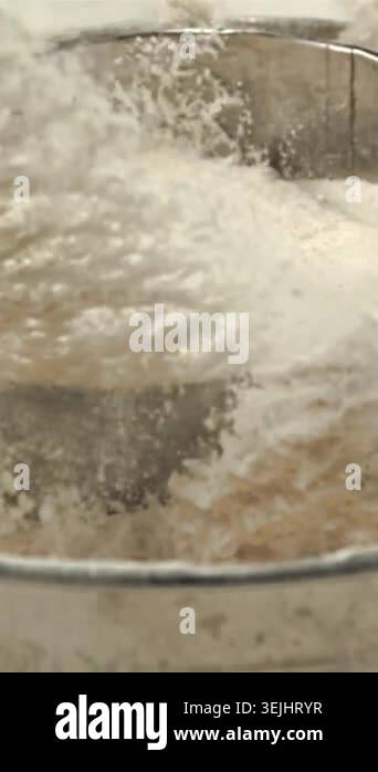 Super slow motion of the flour sieve falls with splashes of flour ...