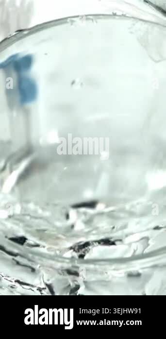 The tablet falls into a glass of water with splashes. On a white ...