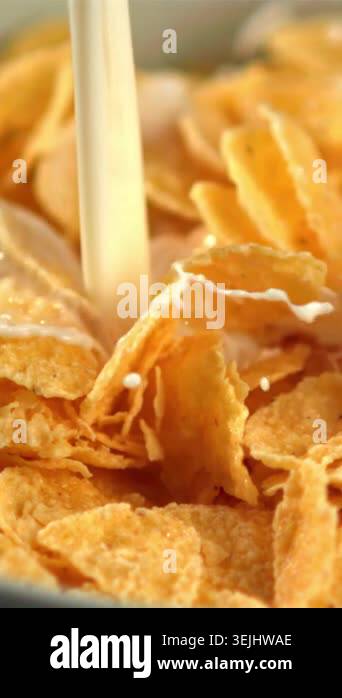 Super slow motion milk pours into a plate of cornflakes. Macro ...