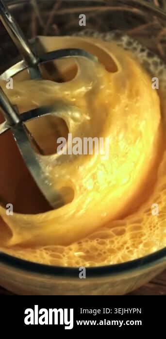 Super slow motion in the bowl beat fresh eggs for omelette. On a wooden ...