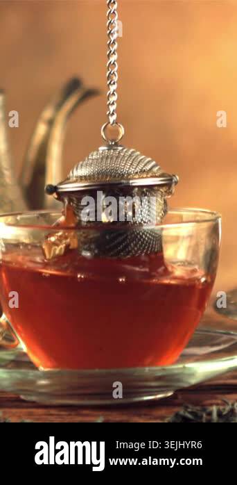Super slow motion from the cup with tea get a sieve with brewing. On a ...