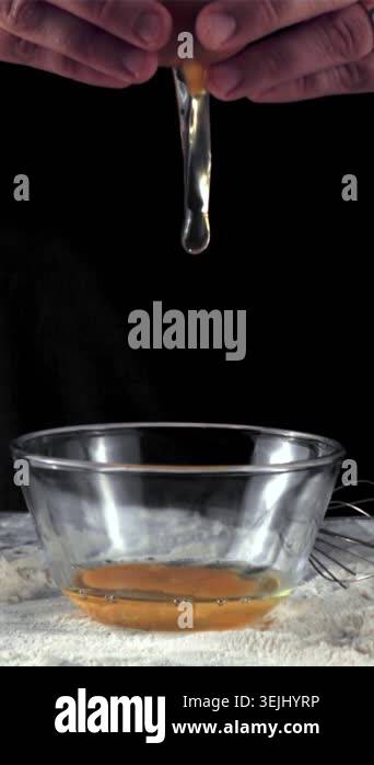 Super slow motion hands cooks break the egg for baking. On a black ...