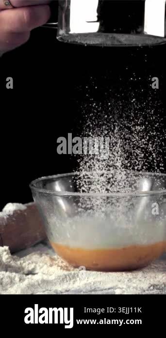 Super slow motion mens hands sprinkle flour in a bowl for baking. On a ...
