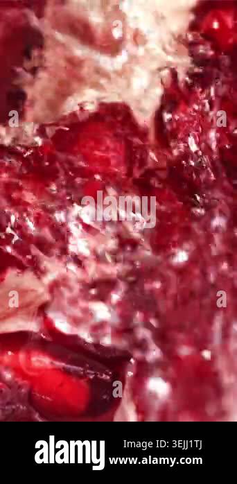 Splashed water pours onto fresh pomegranates. Filmed on a high-speed ...