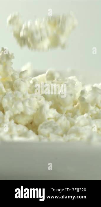 Fresh cottage cheese falls into the plate. Filmed on a high-speed ...