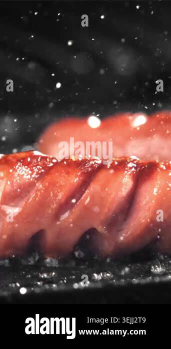 Sausages are fried with splashes in a pan. Filmed on a high-speed ...