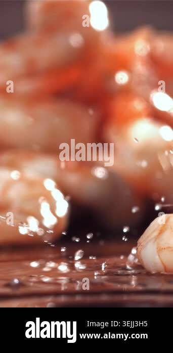 The shrimp falls on a wooden cutting board. Filmed on a high-speed ...