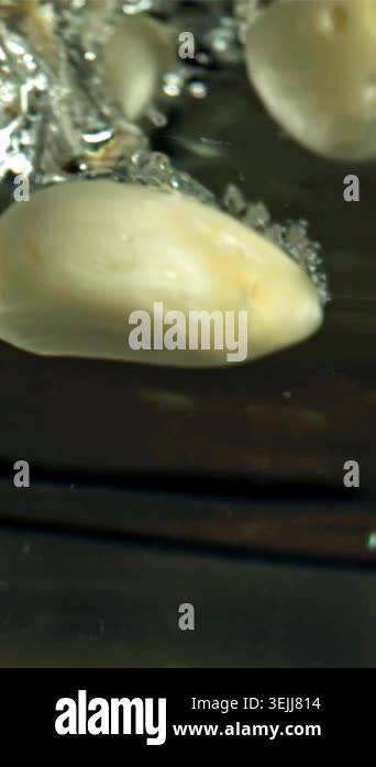 Peeled garlic falls under water. Filmed on a high-speed camera at 1000 ...