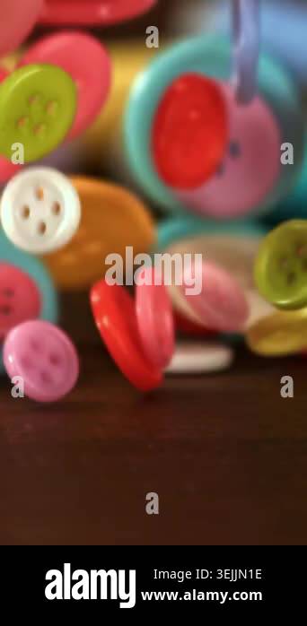 Sewing buttons fall on a wooden table. Filmed on a high-speed camera at ...