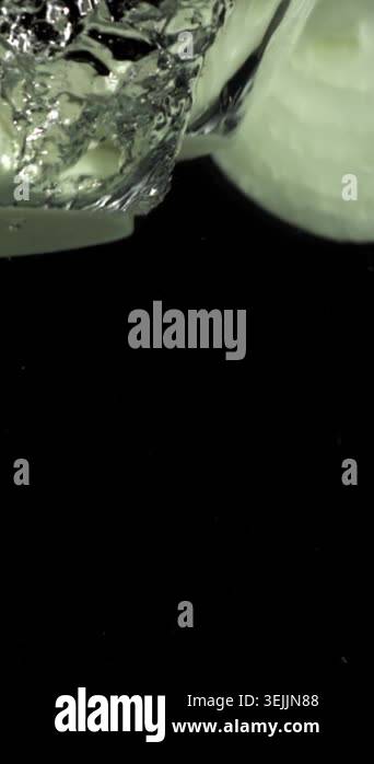 Sliced onion falling into water on black background. Filmed on a high ...