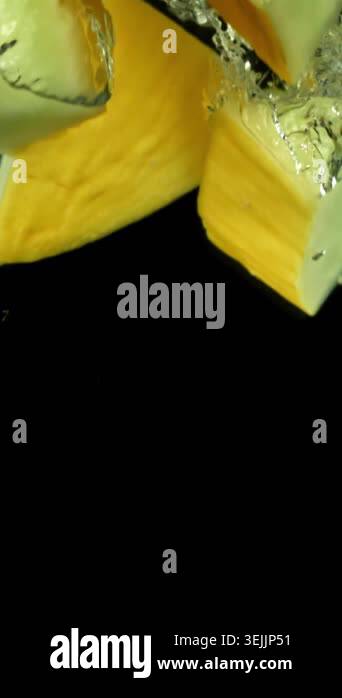 Pieces of melon falling under water on a black background. Filmed on a ...